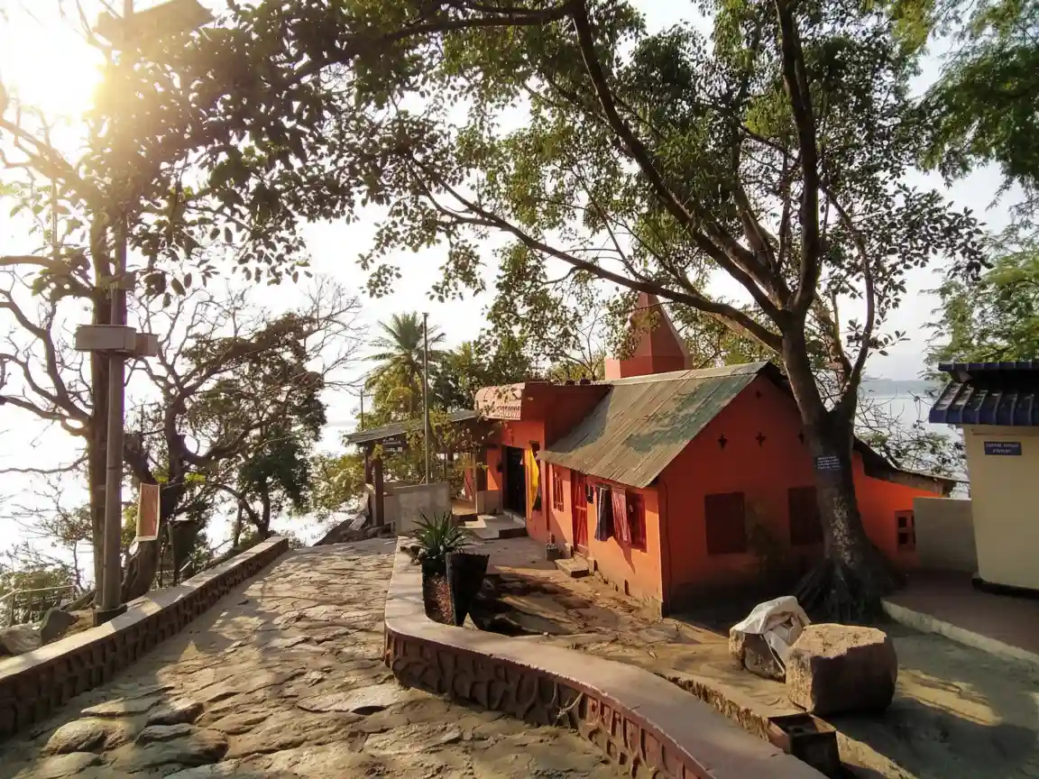 Sun-dappled path leading to the riverside Umananda Temple, with orange ...
